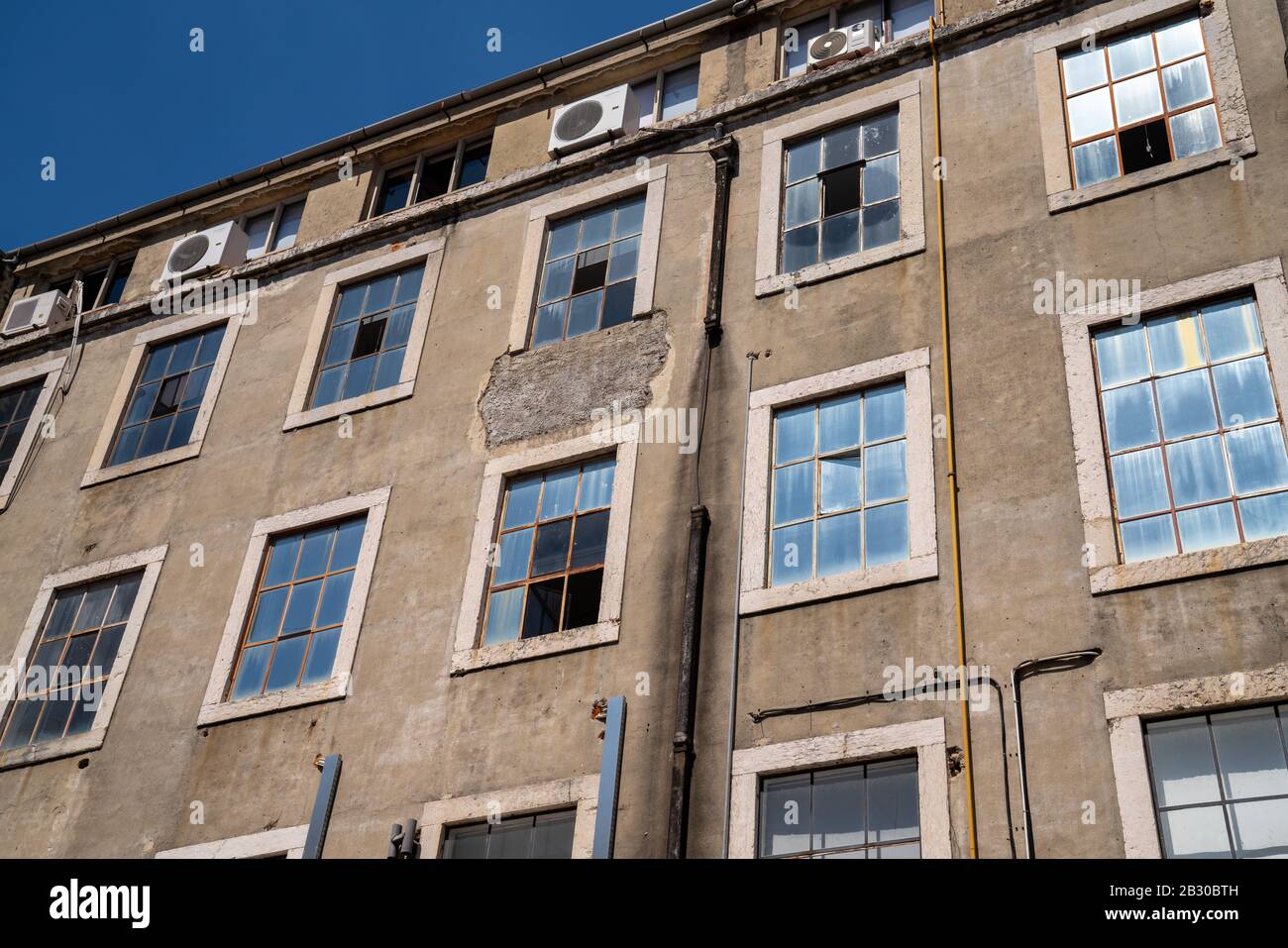 Outside of warehouse with dirty windows, peeling walls, and missing ...