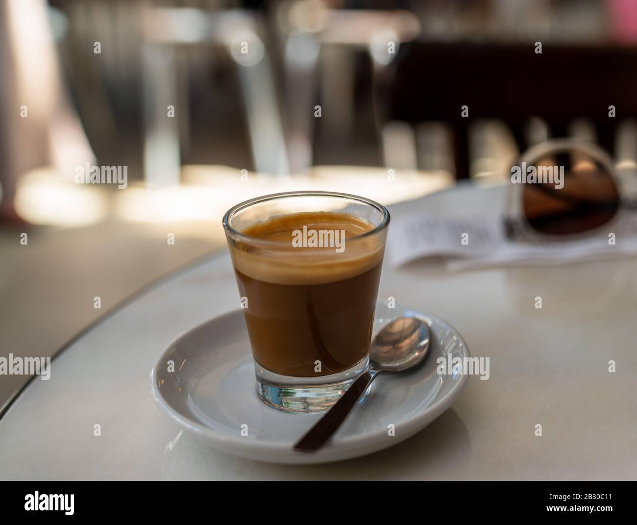 Expresso coffee in small glass with spoon on white table in restaurant ...