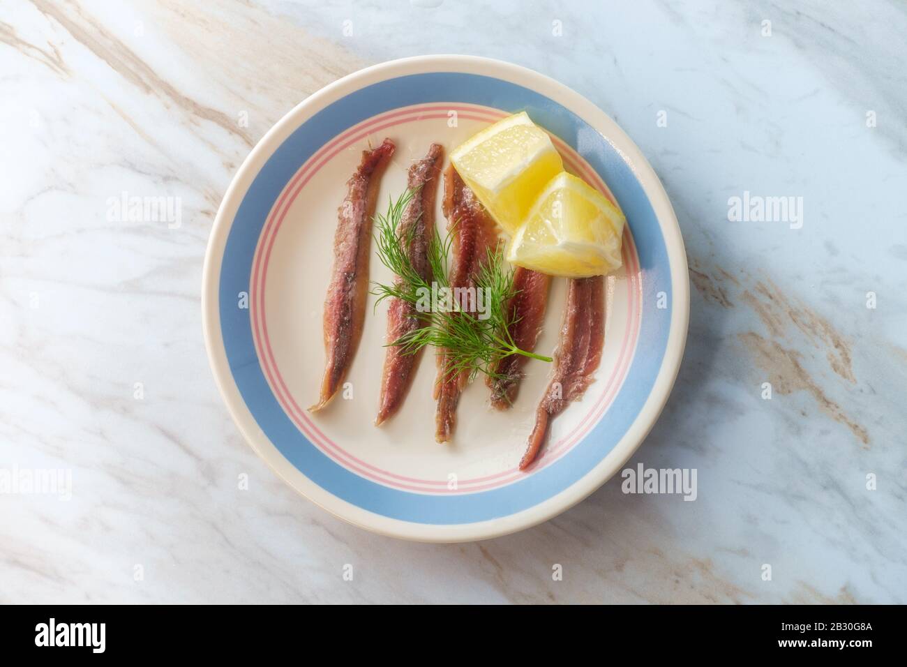 Anchovy fillet in olive oil with dill and lemon garnish Stock Photo - Alamy