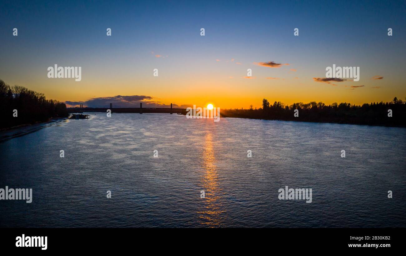 Aerial of sun setting over river bridge in the background Stock Photo ...