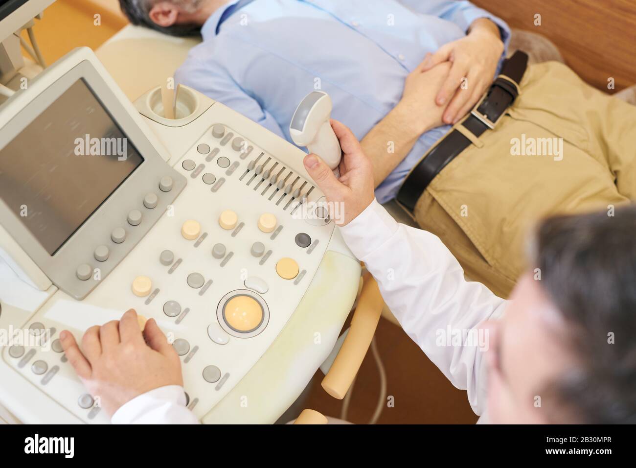 Above view of doctor with transducer probe in hand adjusting ...