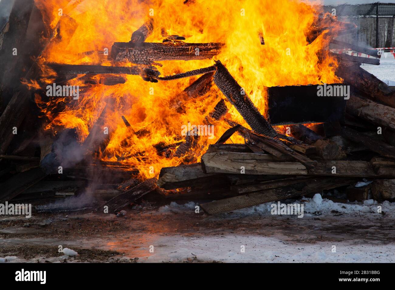 Open fire from burning logs of an old house. Snow is hidden from the ...