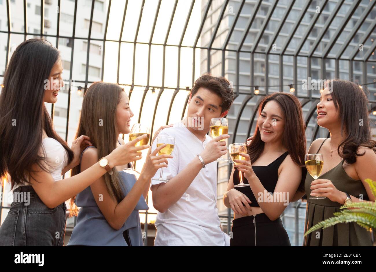 Group of asian multiple gender holding glass of wine chat together with ...