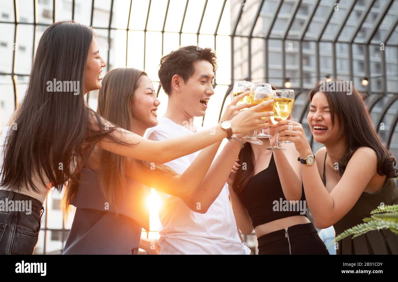 Group of asian multiple gender holding glass of wine chat together with ...