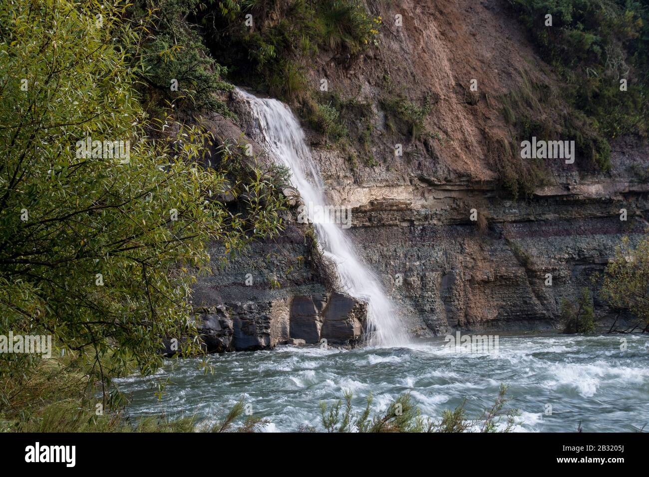 Small cascading waterfall flowing into river after heavy rains Stock ...