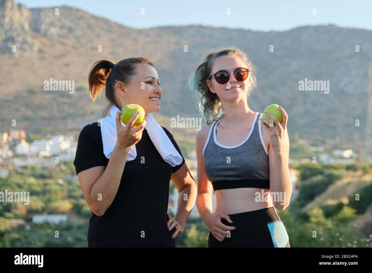 Family mother and daughter eating apples after exercise, jogging in ...