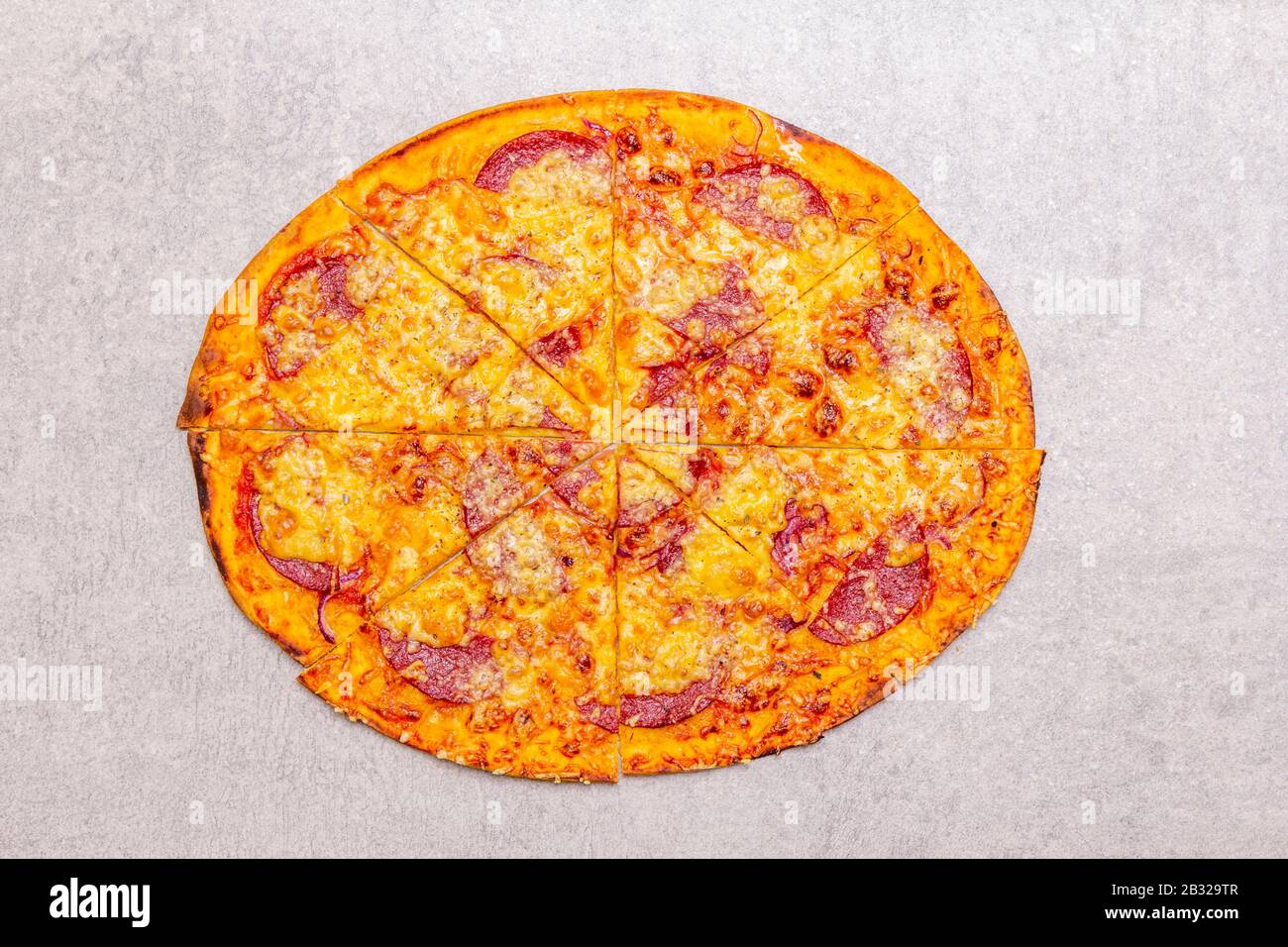 Oval Italian pizza with tomato sauce, salami, red onion, Italian herbs ...