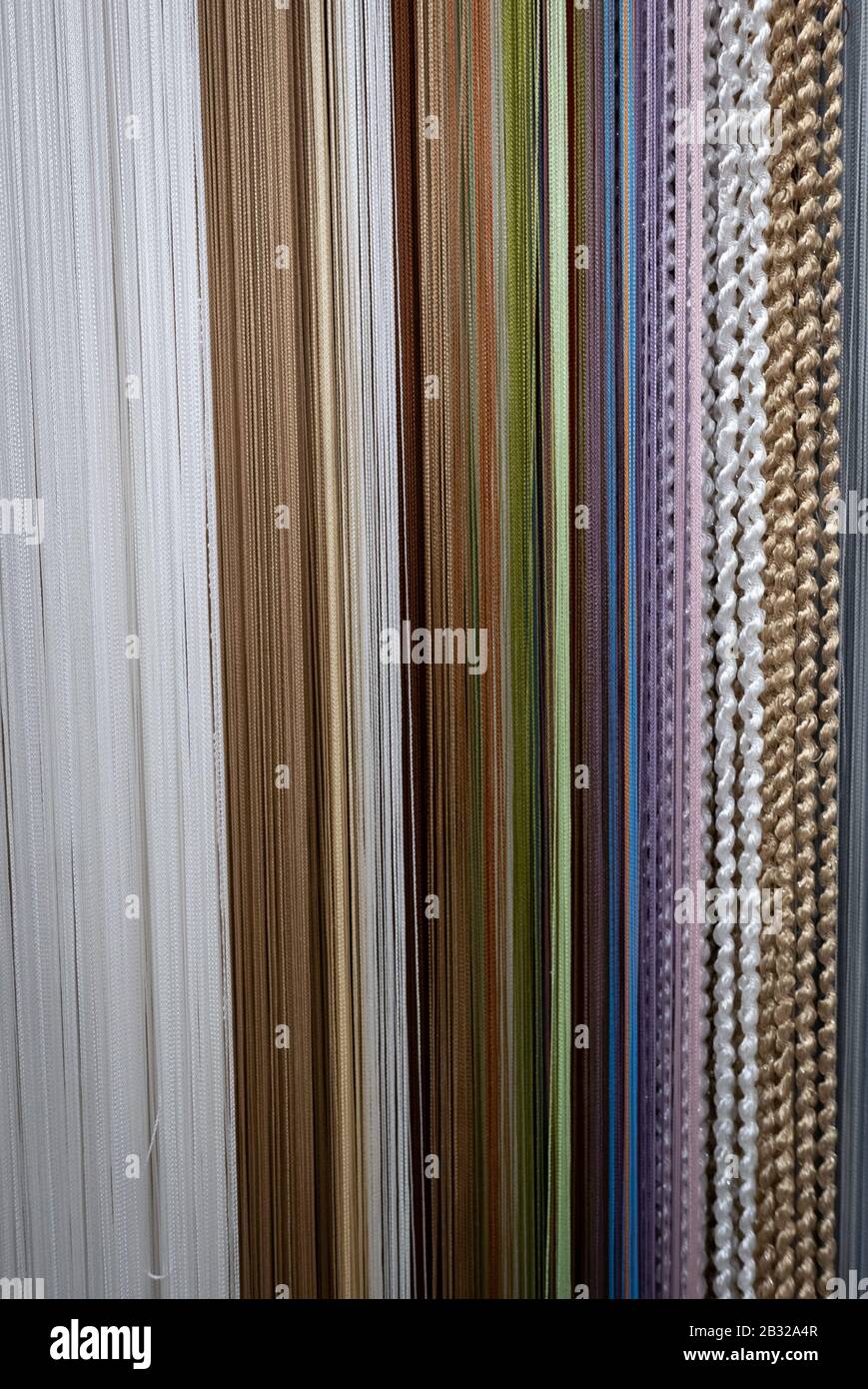 Textile strings and ropes hangs in a fabric shop. Abstract background ...