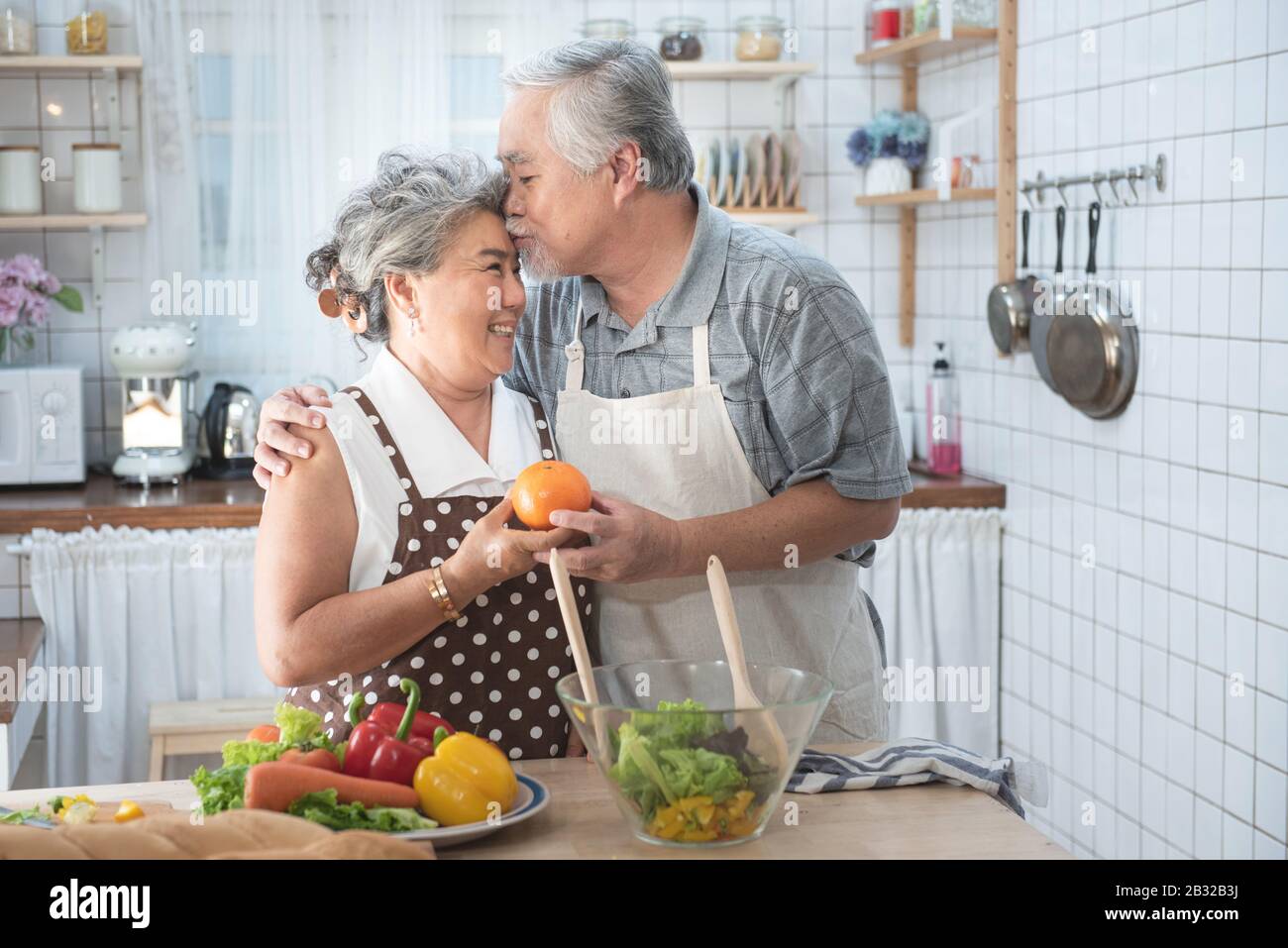 Senior couple having fun in kitchen with healthy food - Retired people ...
