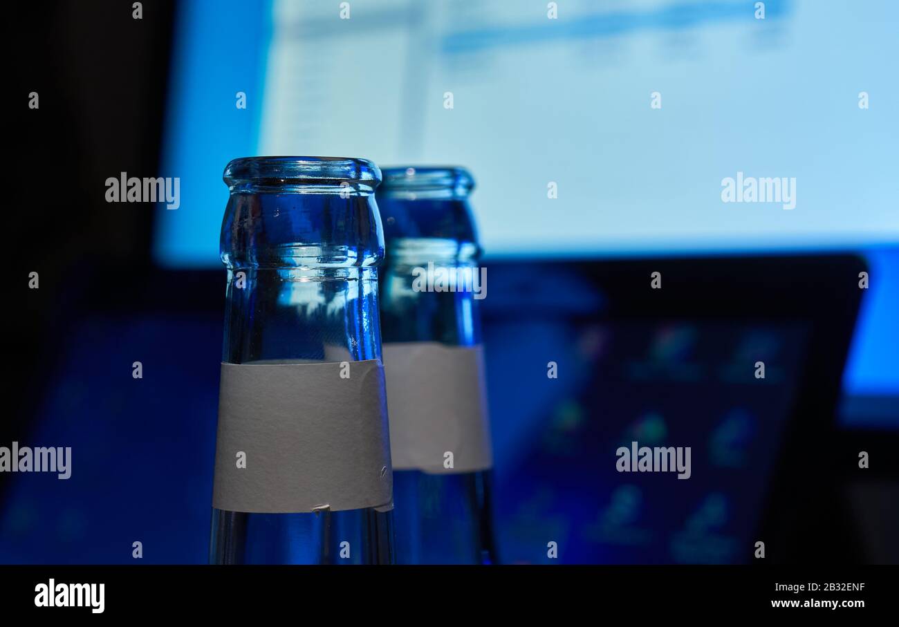 Empty beer bottles, upper part, in front of a switched on computer ...