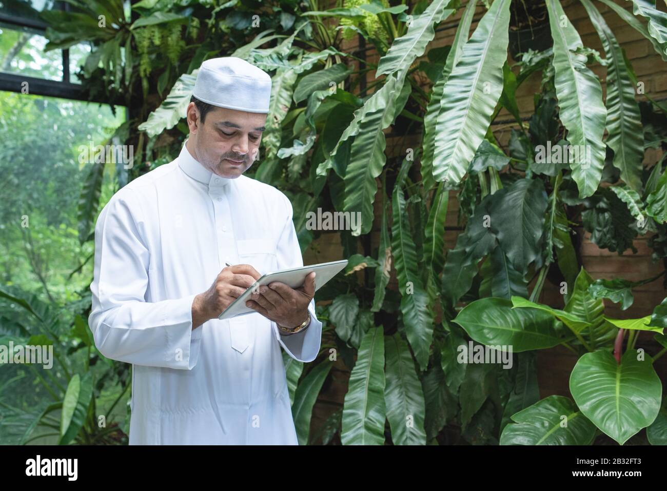 Pakistani business asian man using tablet,standing in green cafe wear ...