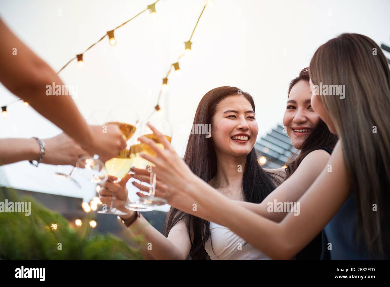 Group of asian multiple gender holding glass of wine chat together with ...