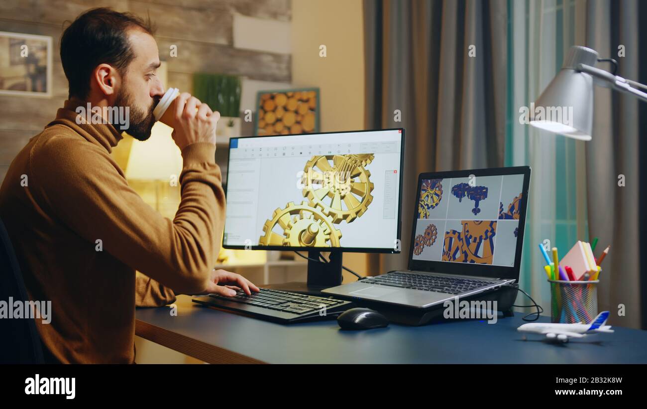 Bearded engineer taking a sip of coffee while working on computer ...