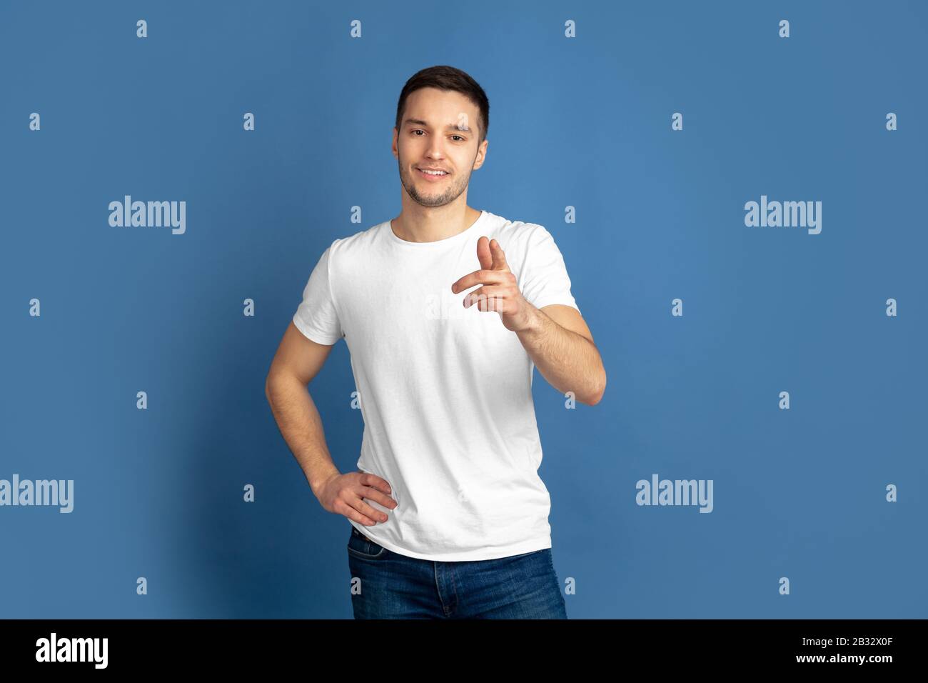 Pointing, choosing. Caucasian young man's portrait isolated on blue ...