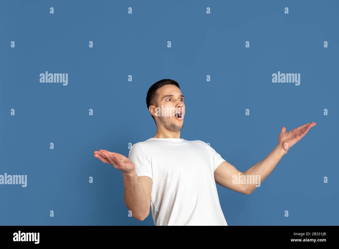 Astonished, shocked. Caucasian young man's portrait isolated on blue ...