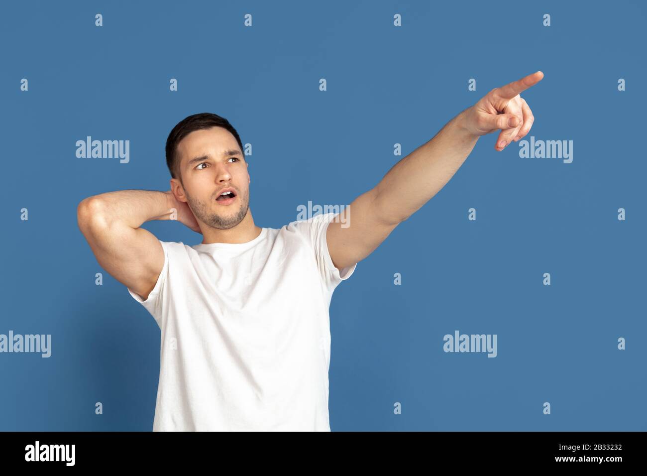 Pointing, choosing. Caucasian young man's portrait isolated on blue ...