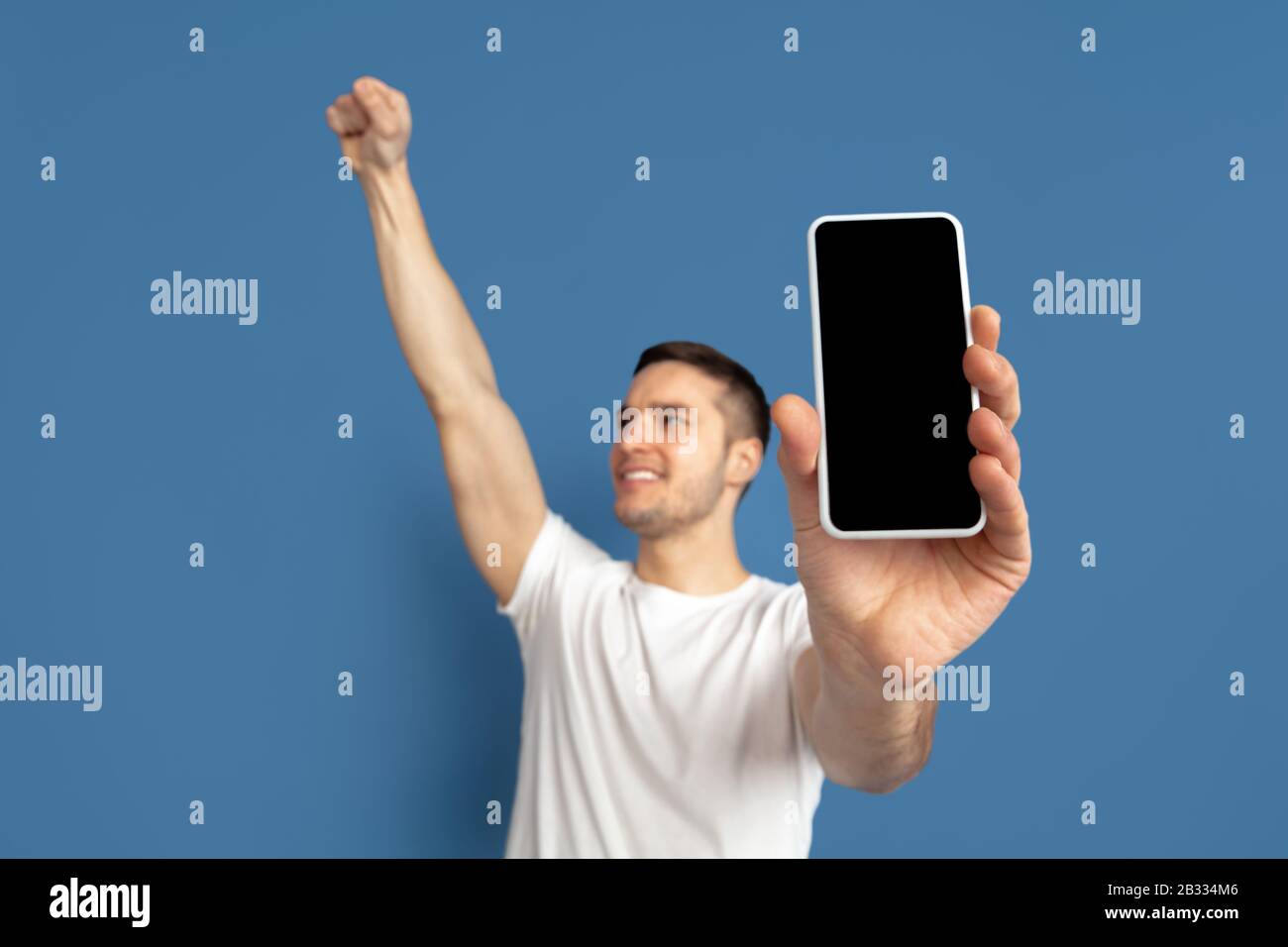 Showing blank screen. Caucasian young man's portrait isolated on blue ...