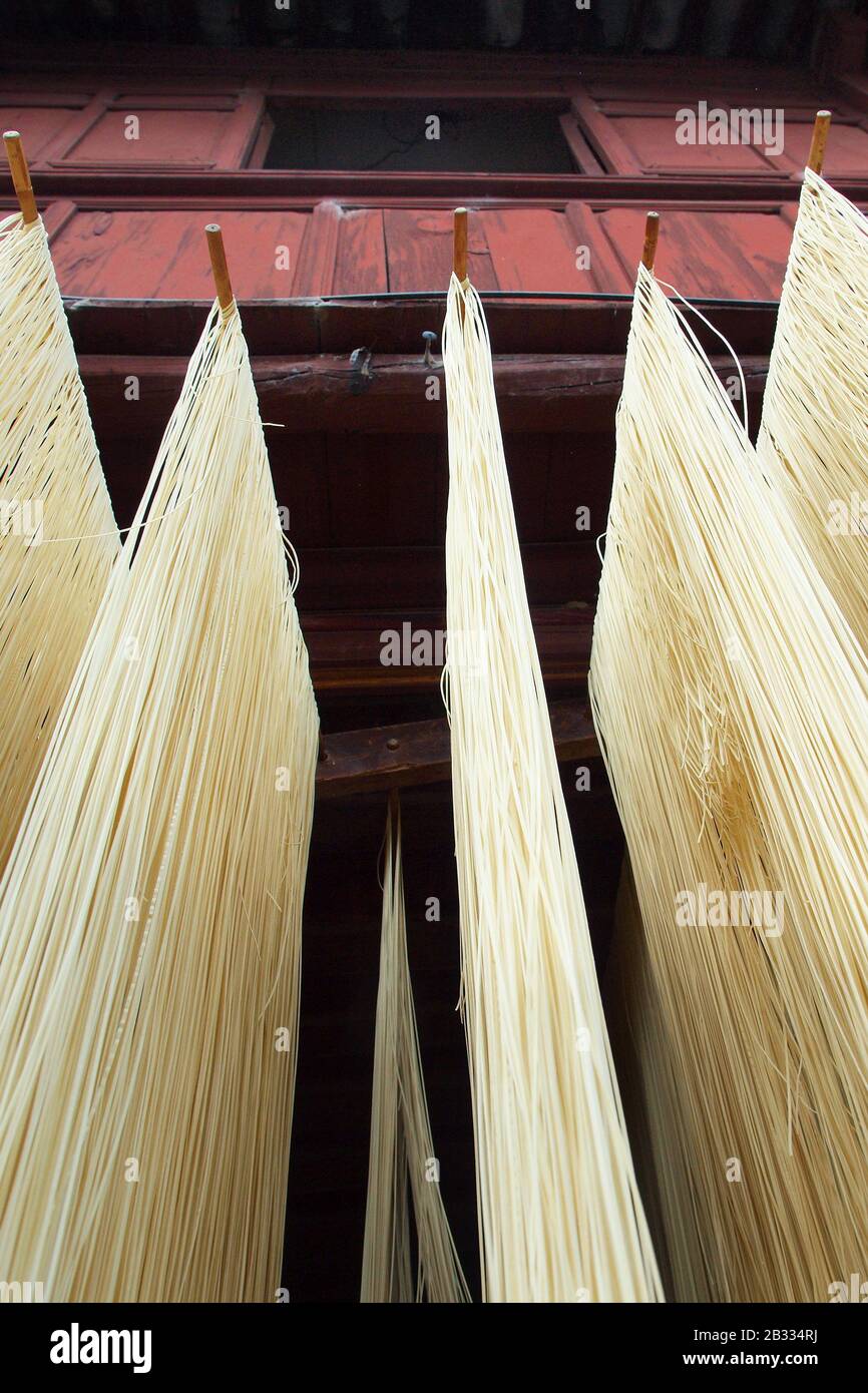 Fresh noodle drying on drying rack, in front of traditional asian house ...