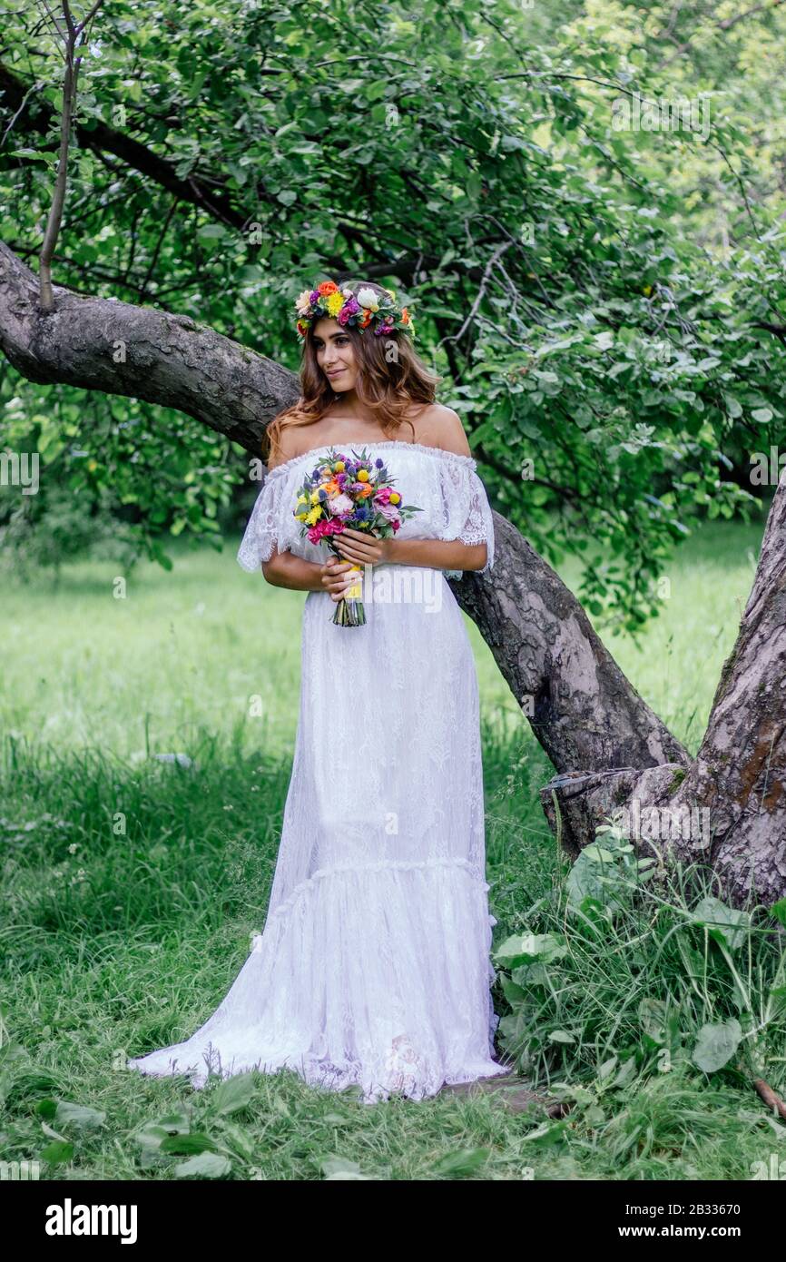 Beautiful bride in green forest near old tree Stock Photo - Alamy