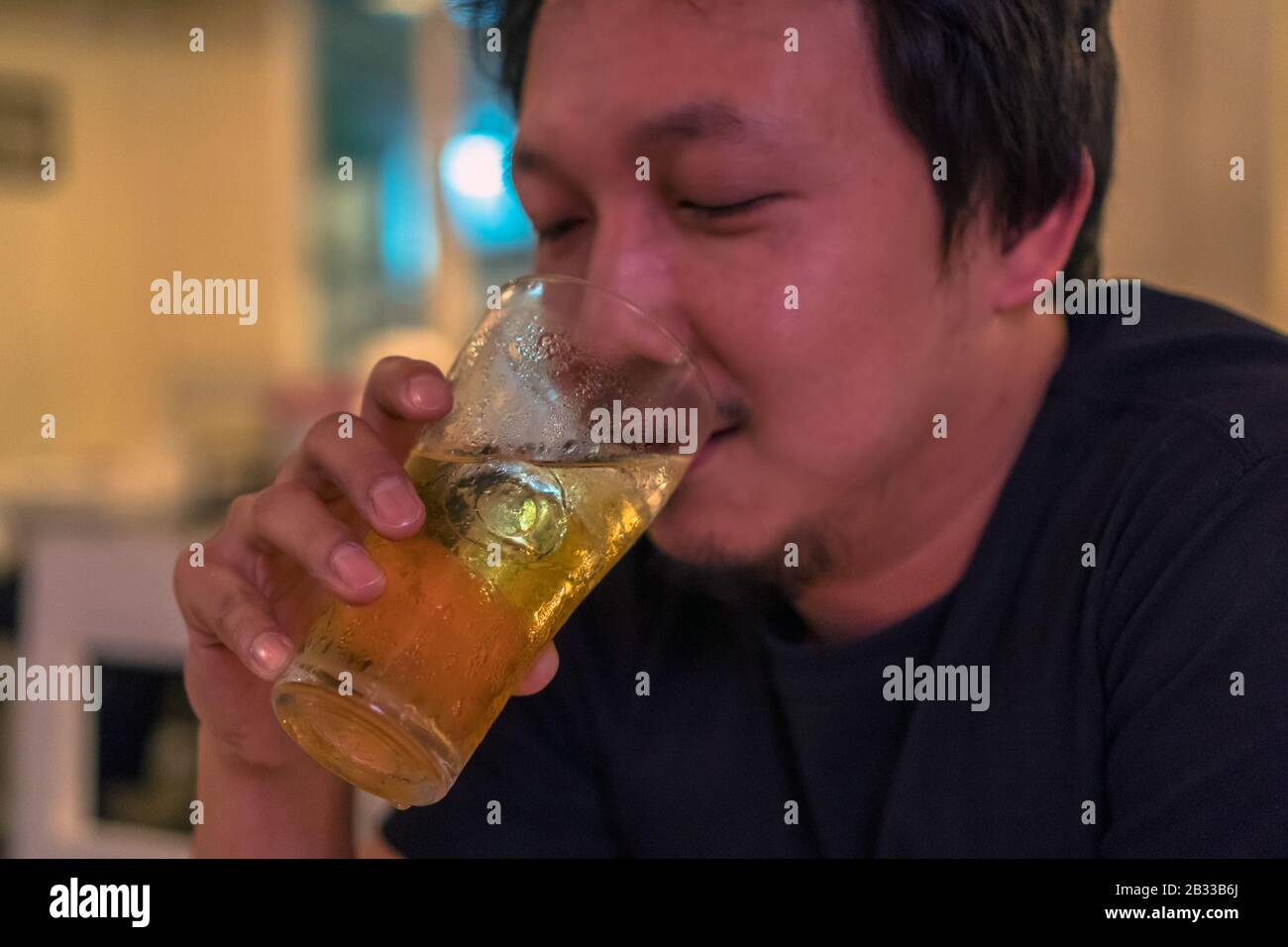 Closeup Asian young man in happiness action and drinking beer in pub ...
