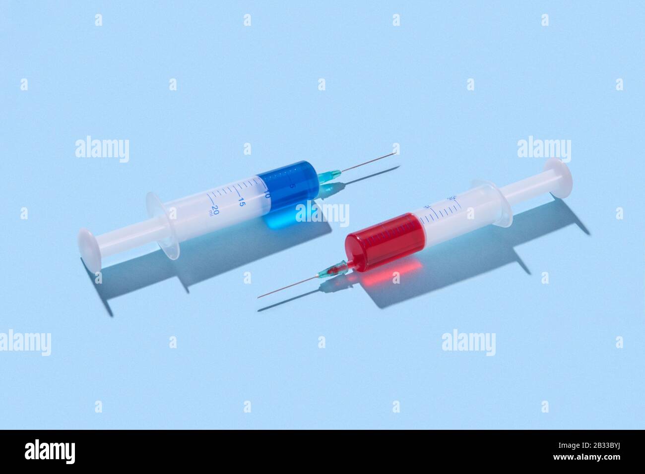 Plastic syringes of red and blue vaccine with shadows Stock Photo - Alamy