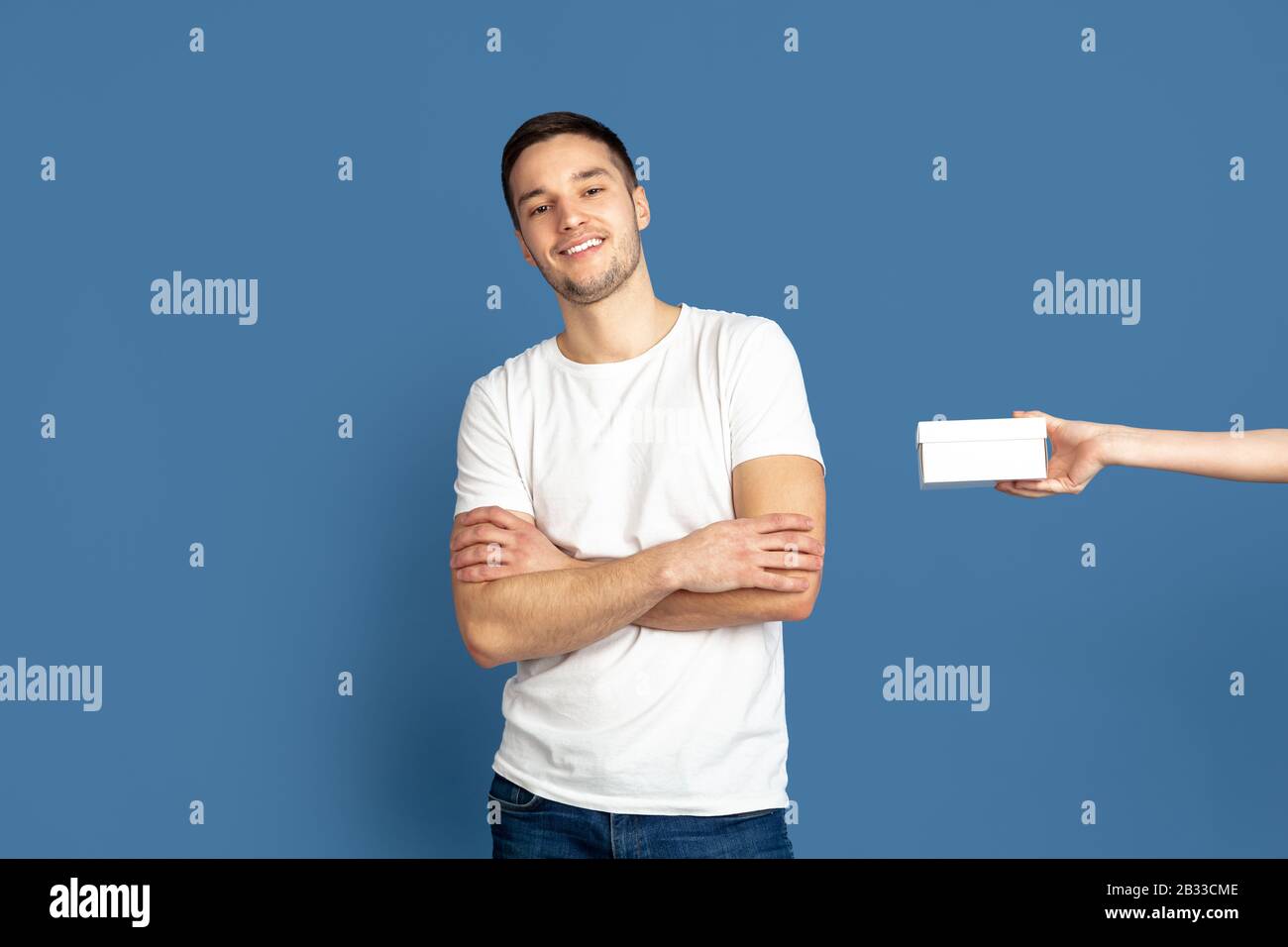 Getting a giftbox. Caucasian young man's portrait on blue studio ...