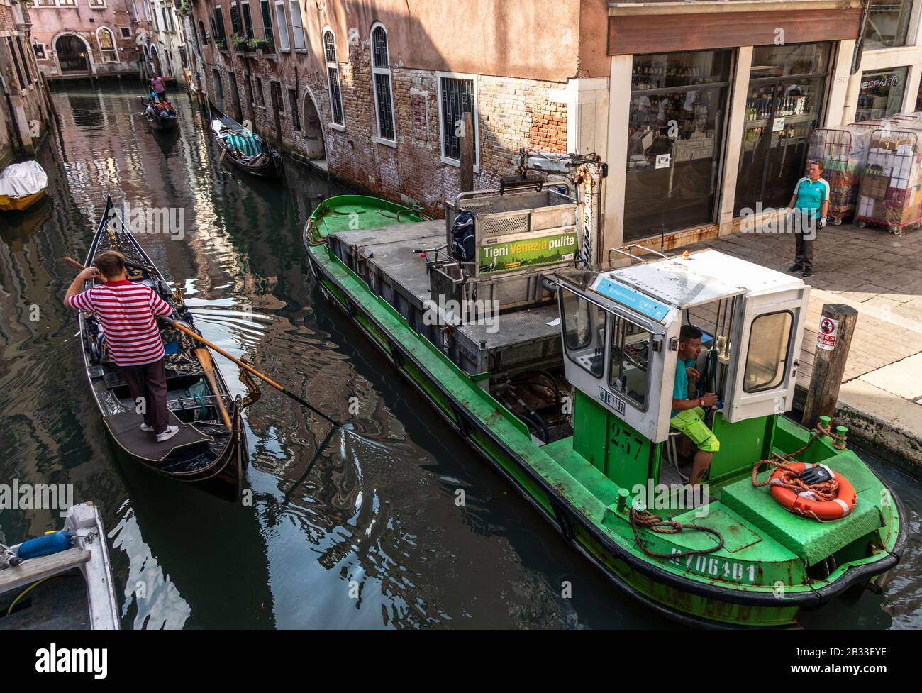 Green rubbish/garbage collection barge stopped to collect daily rubbish ...