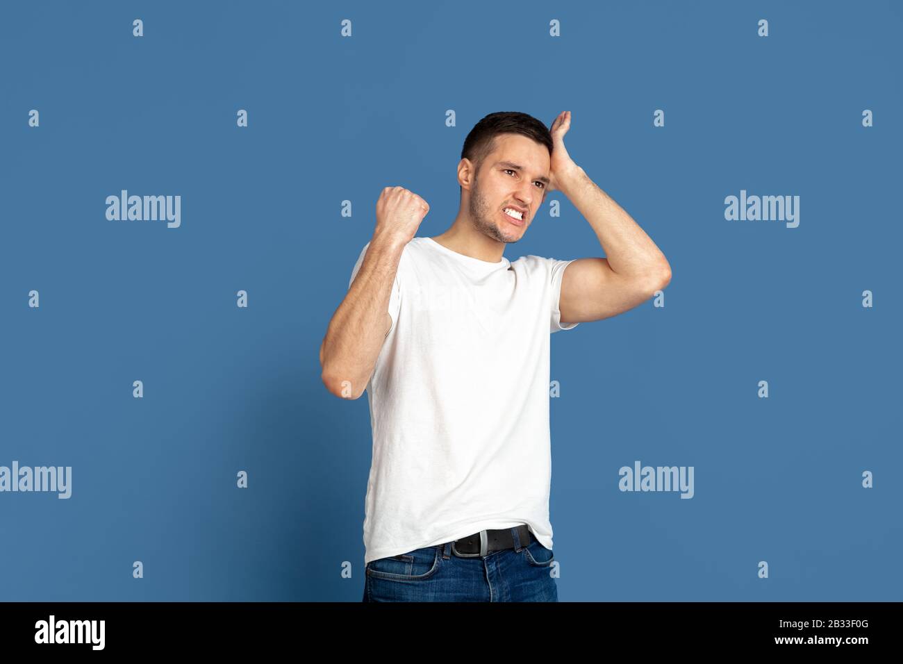 Excited, angry and disappointed. Caucasian young man's portrait on blue ...