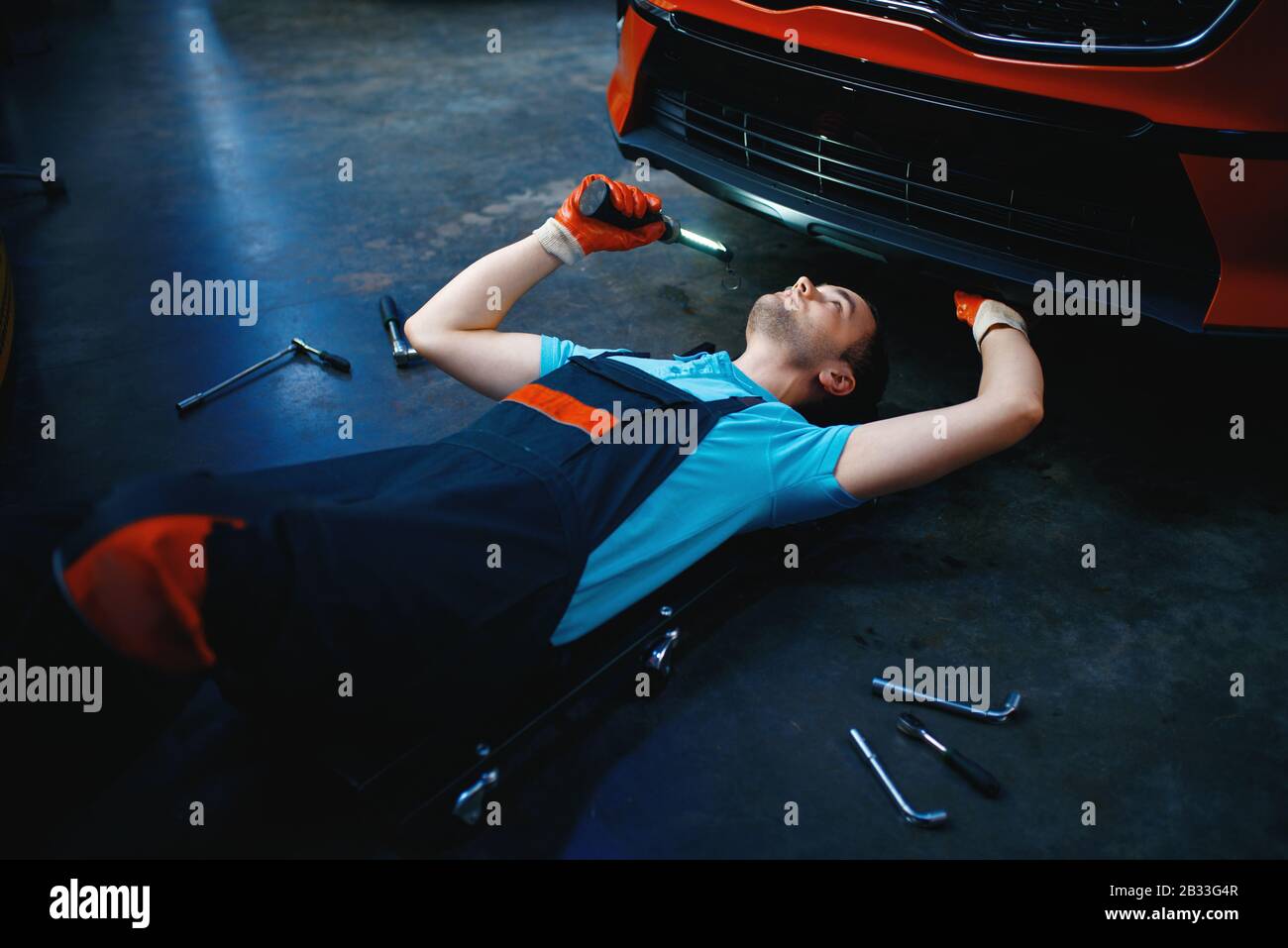 Worker lying under the vehicle, car service Stock Photo - Alamy