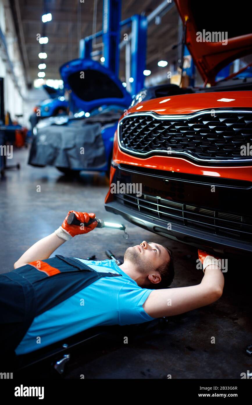 Worker lying under the vehicle, car service Stock Photo - Alamy