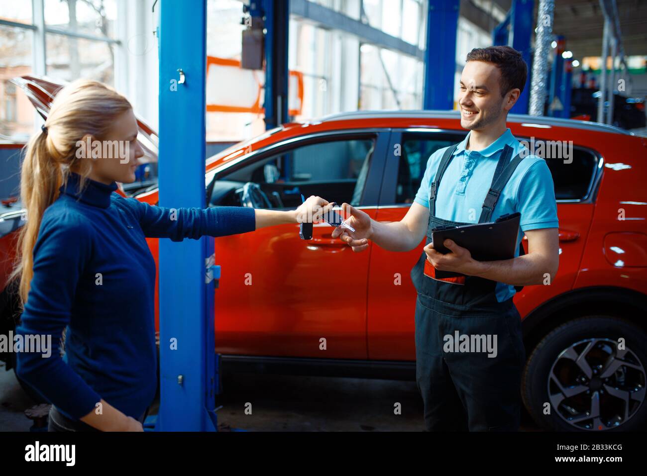 Female driver gives keys to worker in uniform Stock Photo - Alamy