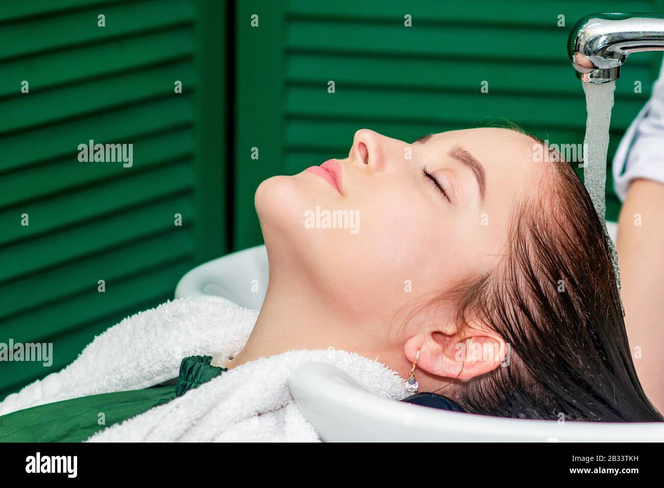 Hairdresser washing hair of woman in sink at beauty salon Stock Photo ...