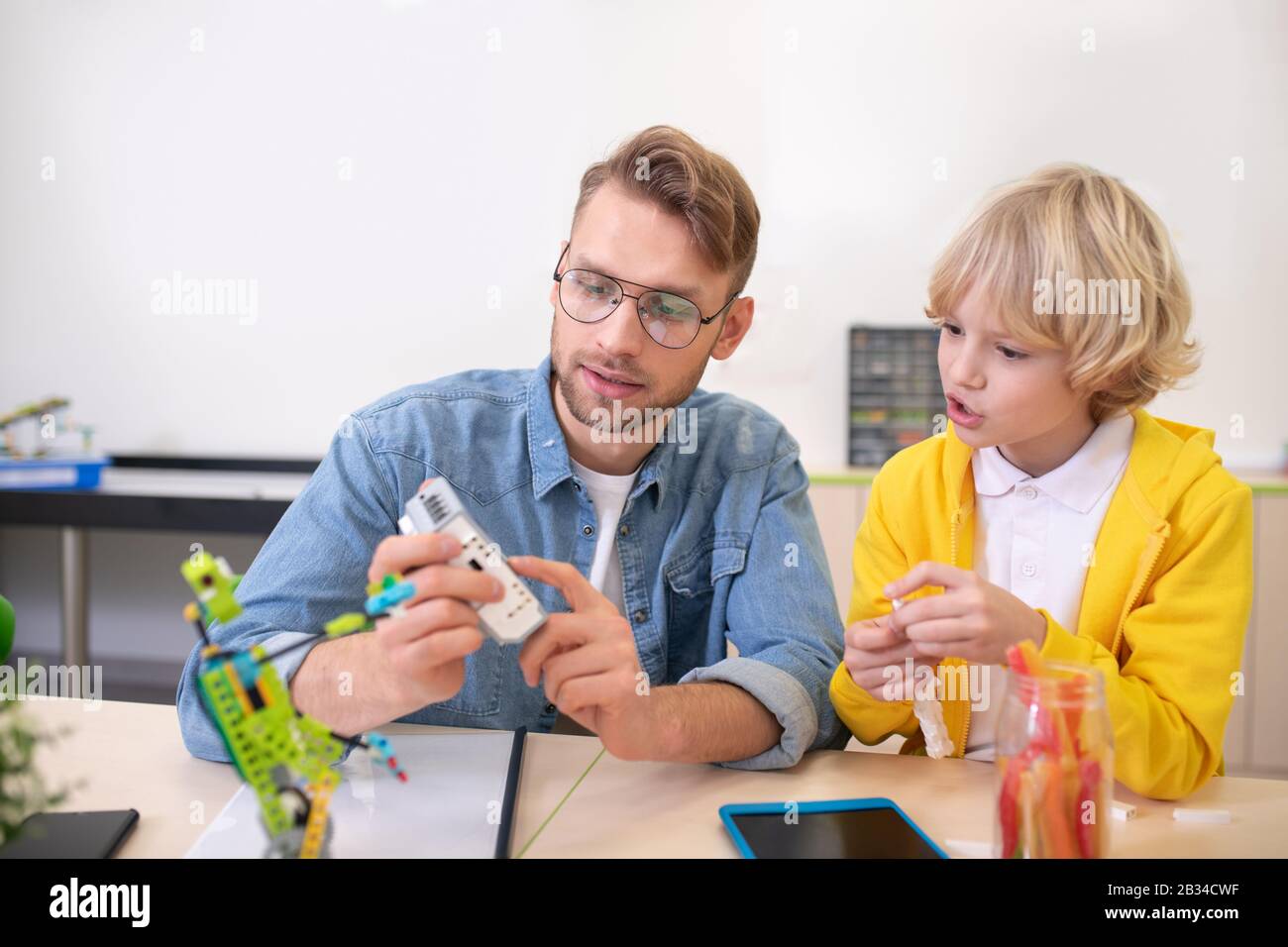 Male teacher explaining boy how control unit works Stock Photo - Alamy