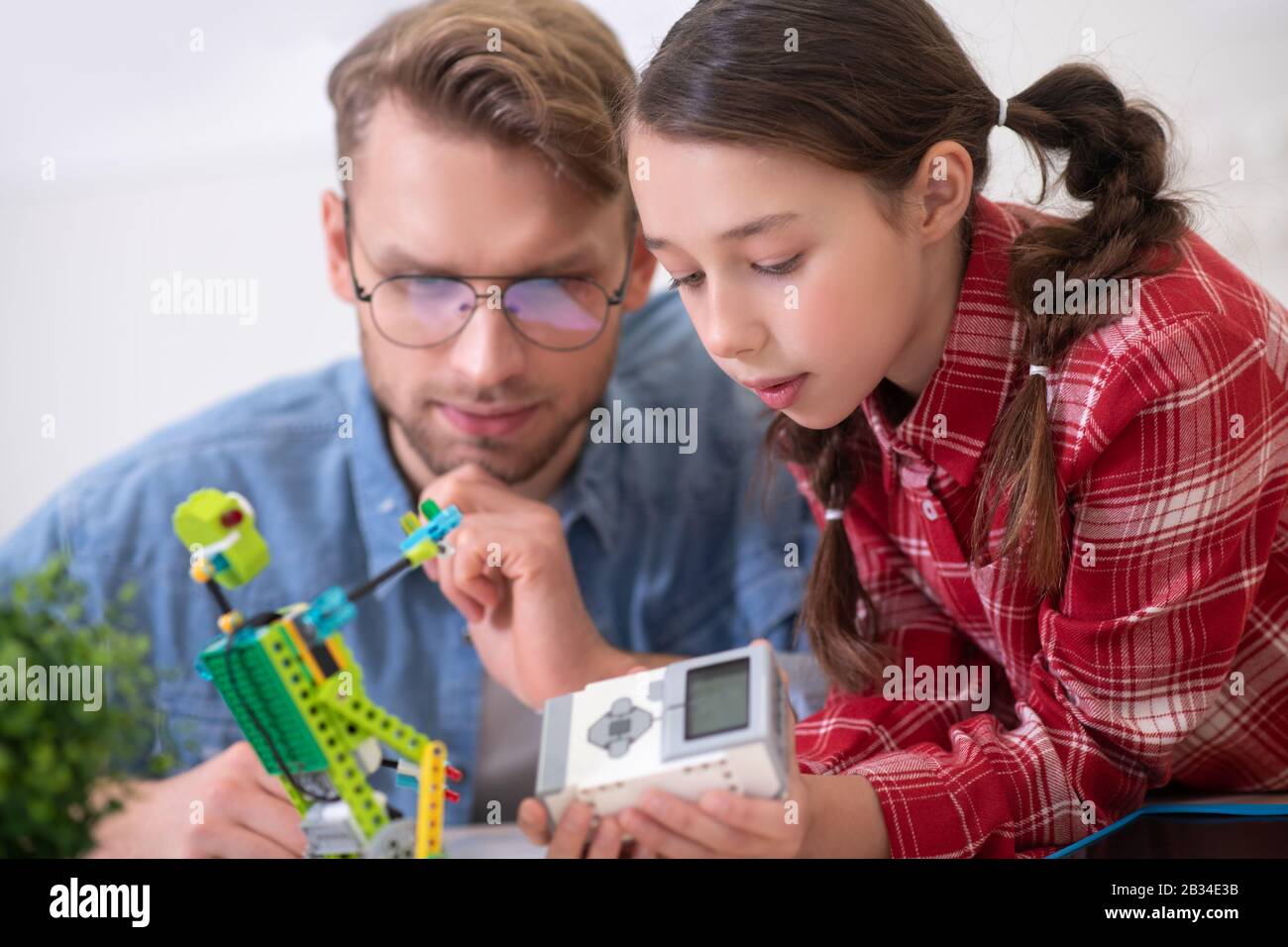 Girl holding control unit, teacher sitting and touching chin Stock ...