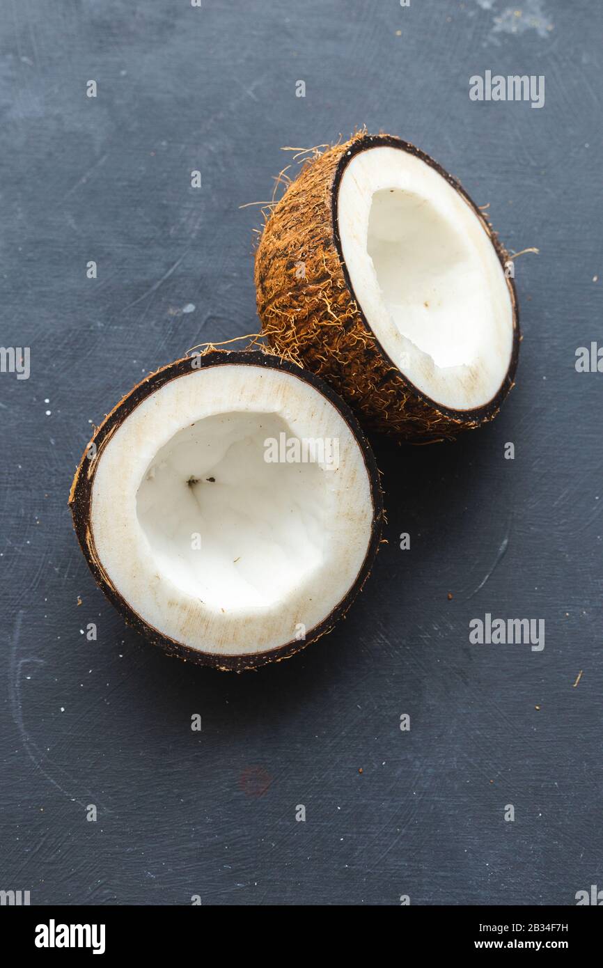 Vertical overhead closeup shot of cut coconuts on a grey background ...