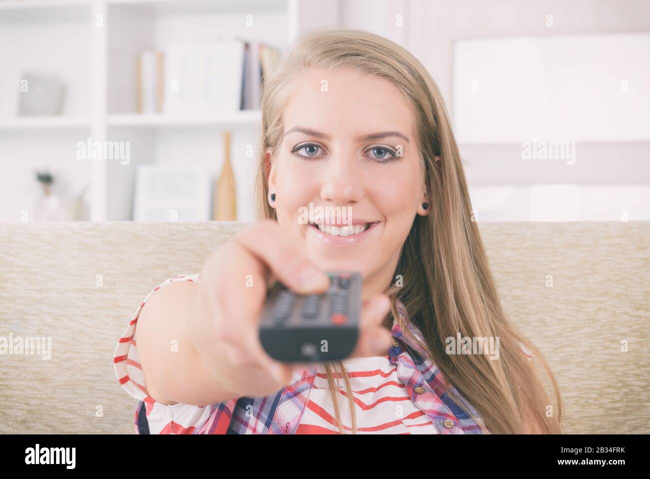 Beautiful young woman holding tv remote control and changing TV ... Beautiful young woman holding tv remote control and changing TV ...
