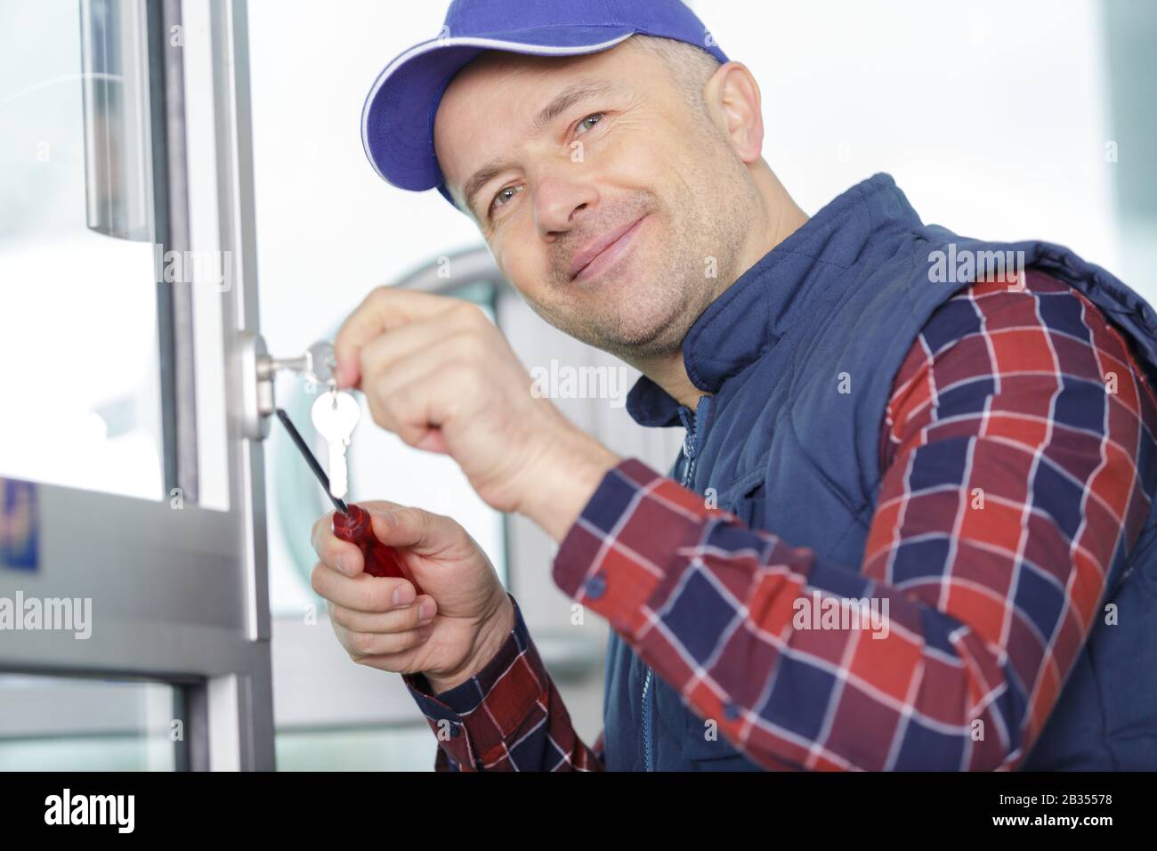 cheerful locksmith installing a door lock Stock Photo - Alamy