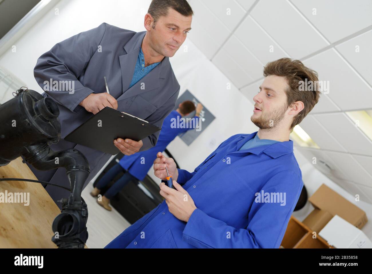 apprentice and teacher with mechanical piece Stock Photo - Alamy