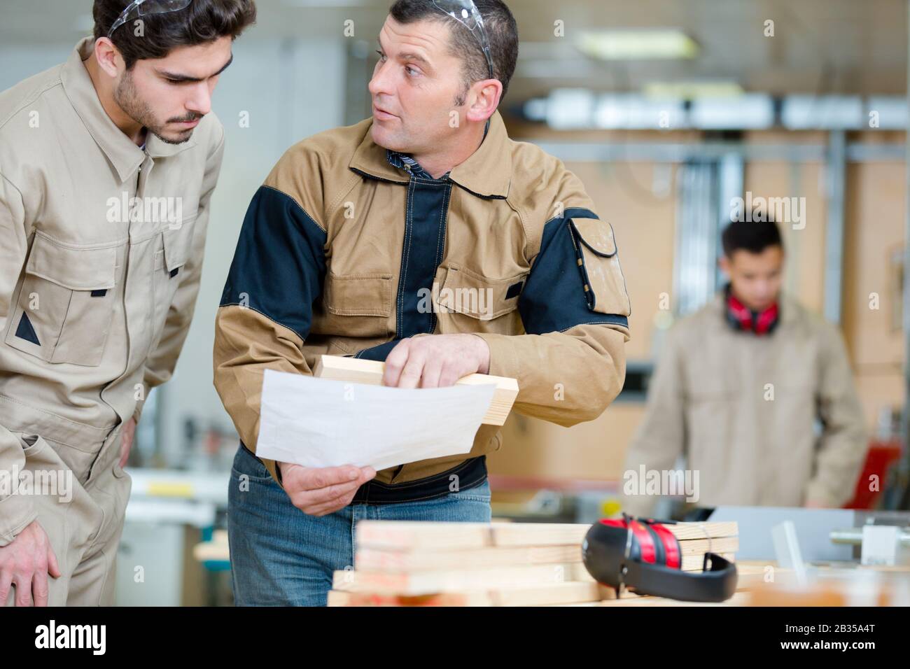 carpentry workers talking holding small plank of industrial wood Stock ...