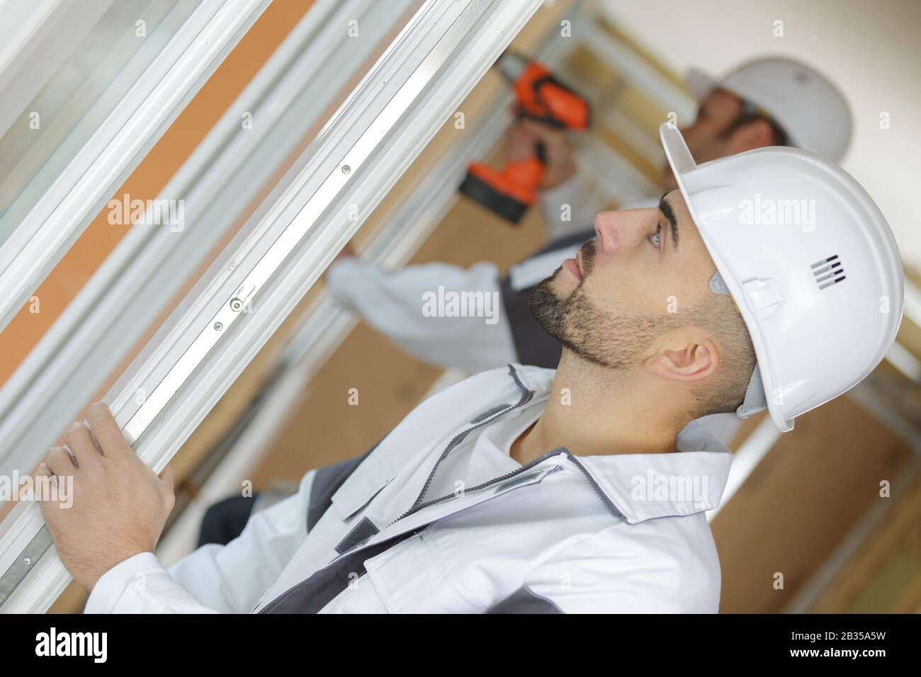 workmen fitting a window at a construction site Stock Photo - Alamy