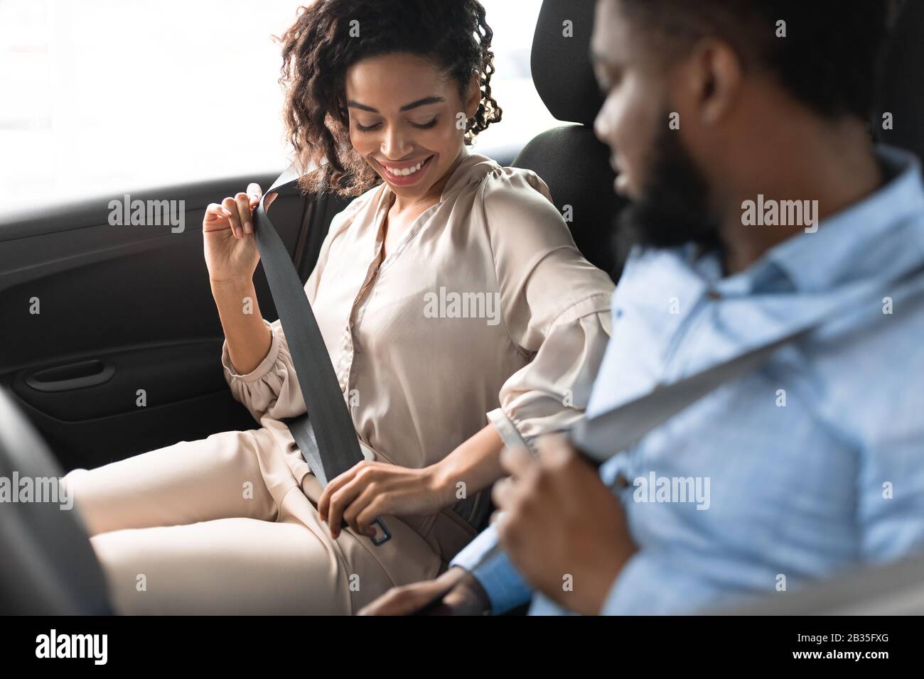 Couple Putting On Seat Belts Testing Automobile In Luxury Showroom ...