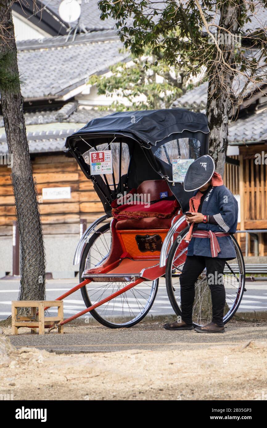 A rickshaw driver waits beside a rickshaw in Nara Park, Nara, Japan ...