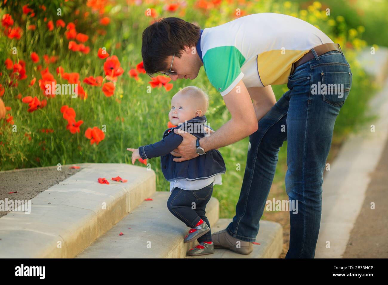 Happy father and child playing together on the poppy meadow. Dad and ...