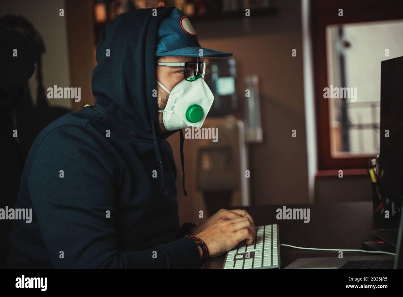 Man infected with corona virus working on computer with respirator mask ...