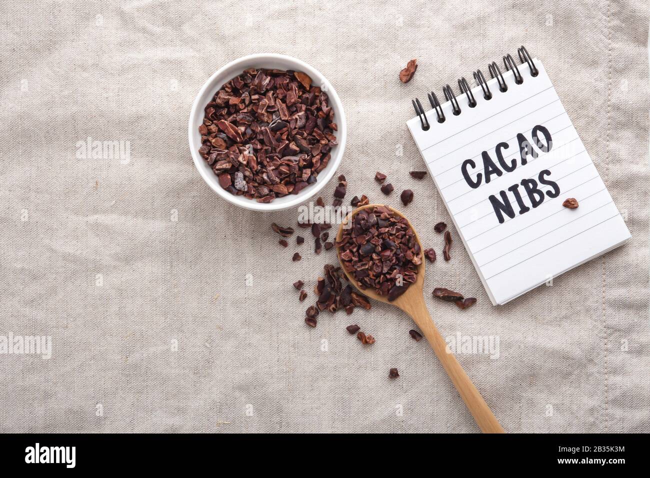 Cacao nibs in white bowl and wooden spoon with handwritten note on ...
