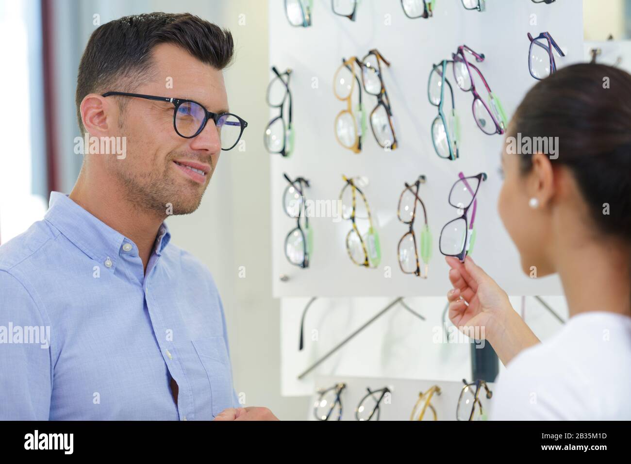 male optician patient and difficult choice of glasses Stock Photo - Alamy