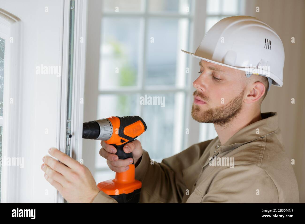 man drilling a hole in a window frame Stock Photo - Alamy
