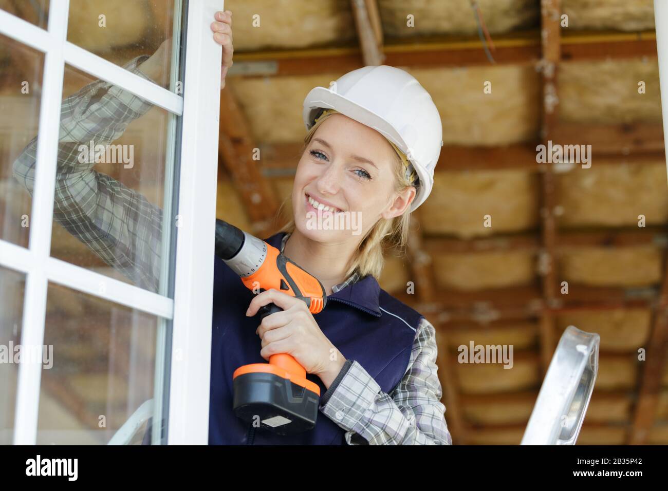happy female builder with drill Stock Photo - Alamy