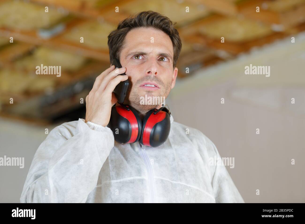 workman wearing earmuffs receiving telephone call Stock Photo - Alamy