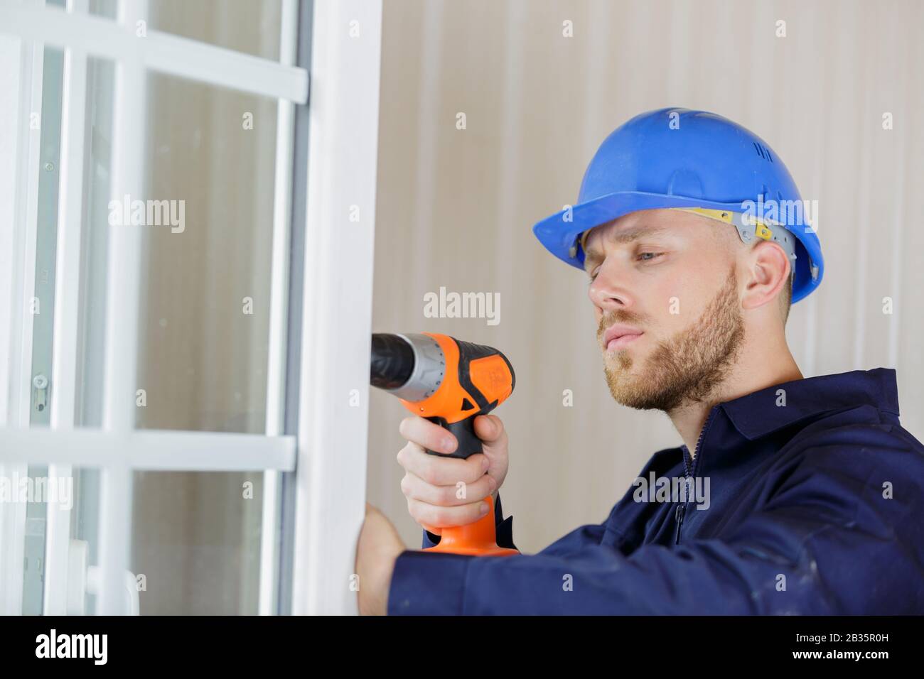 man drilling a hole in a window frame Stock Photo - Alamy
